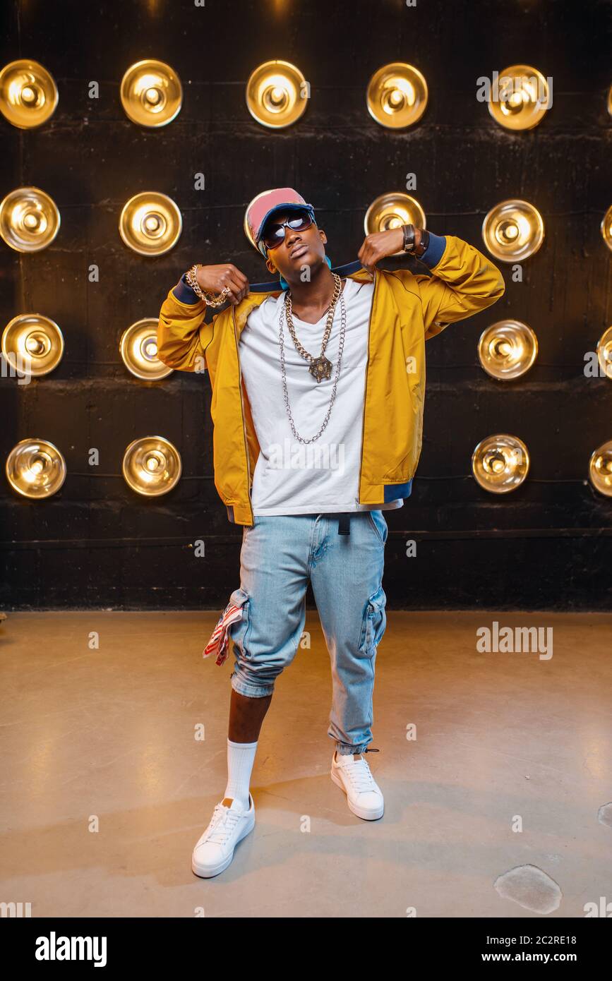 Black rapper in cap, perfomance on stage with spotlights on background ...