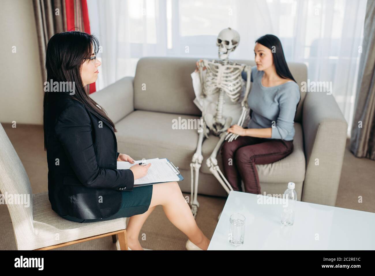 Young woman with human skeleton at psychologist reception. Female ...