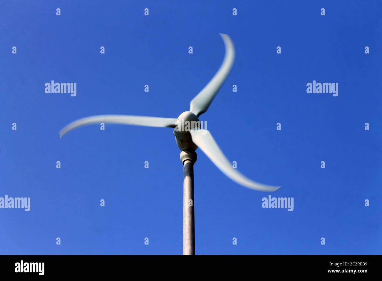 The rotating white windmil in the blue sky Stock Photo - Alamy