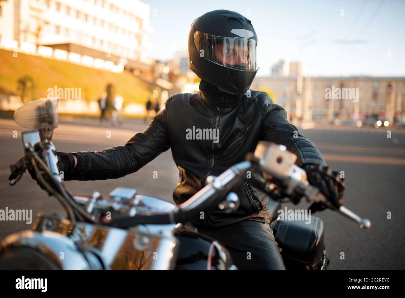 Biker in leather jacket and helmet with visor sitting on classical ...