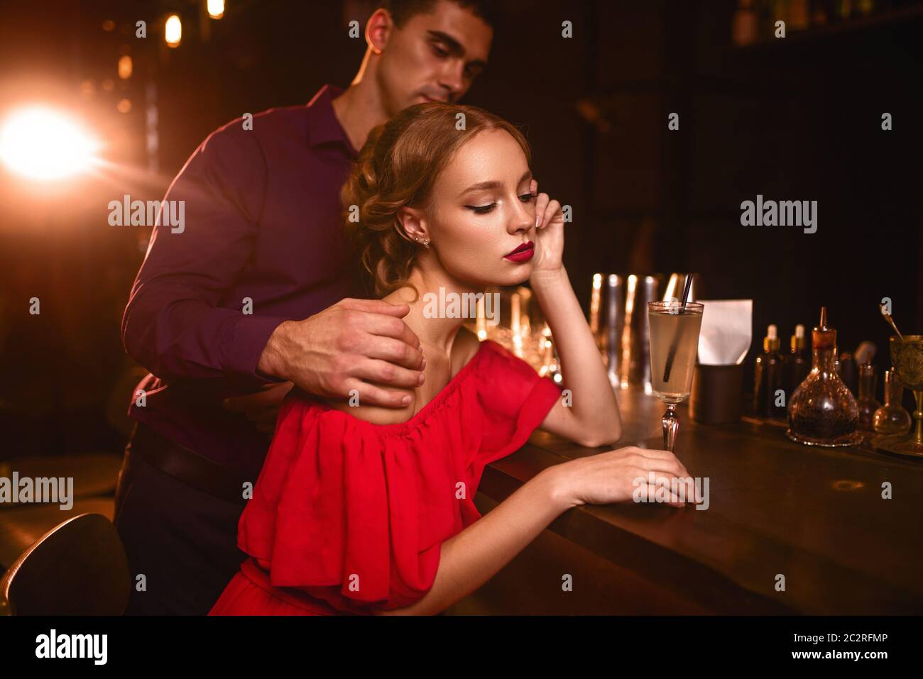 Woman in red dress, man behind bar counter, flirt. Date in nightclub ...