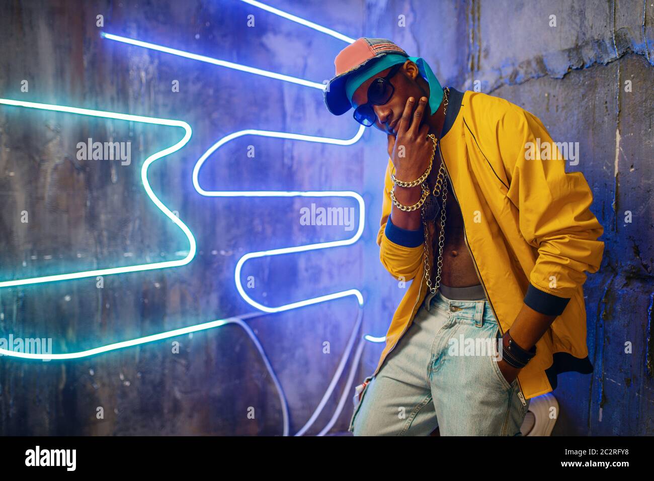 Black rapper in underpass neon lights on background. Rap performer in ...