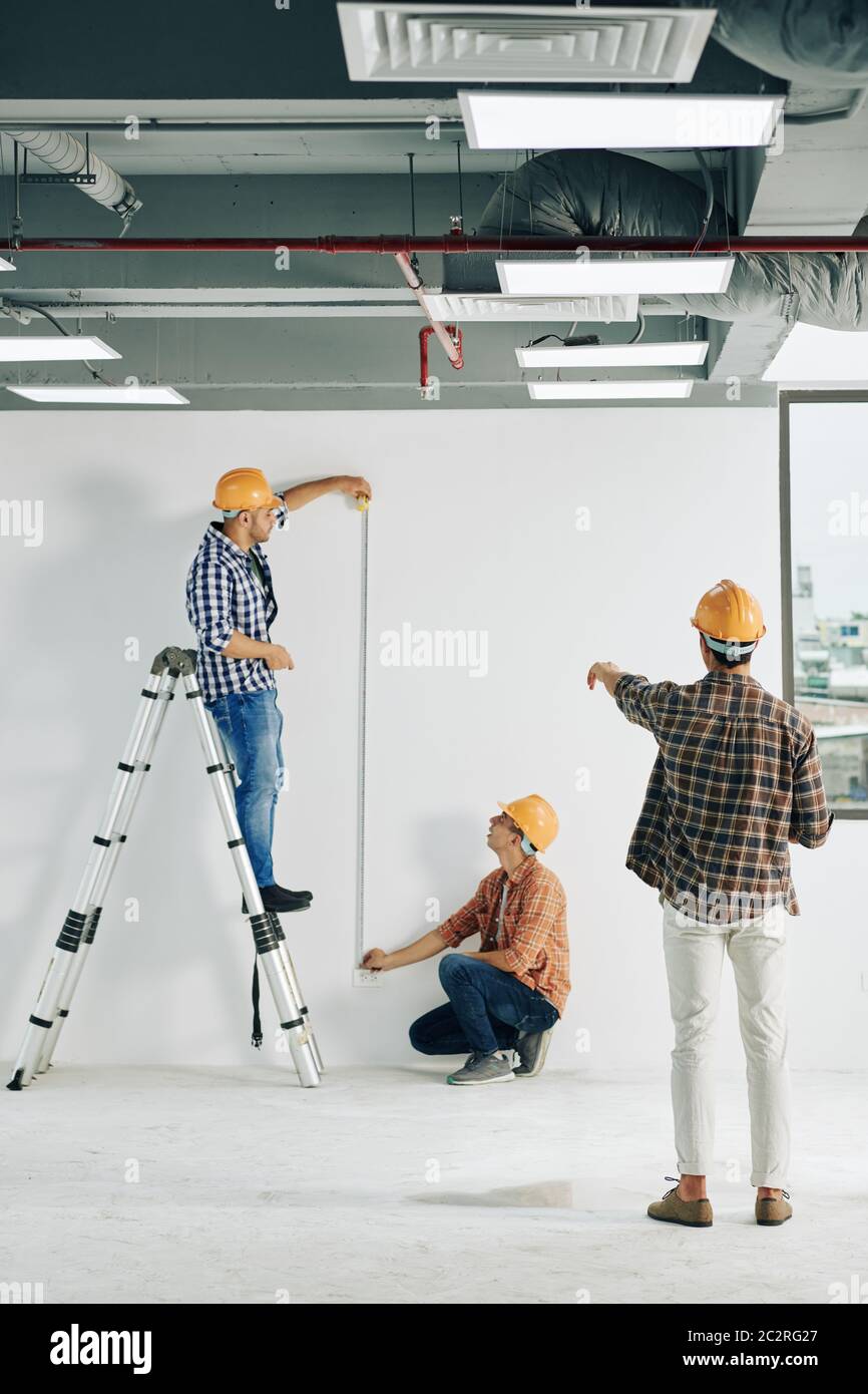 Vertical long shot of professional construction workers taking length ...