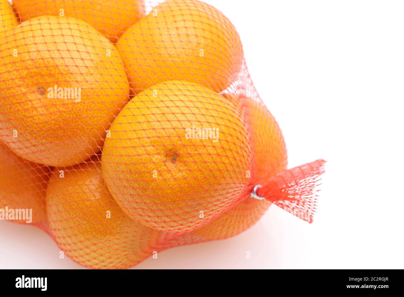 Japanese citrus mikan fruit in a plastic mesh bag on white background ...