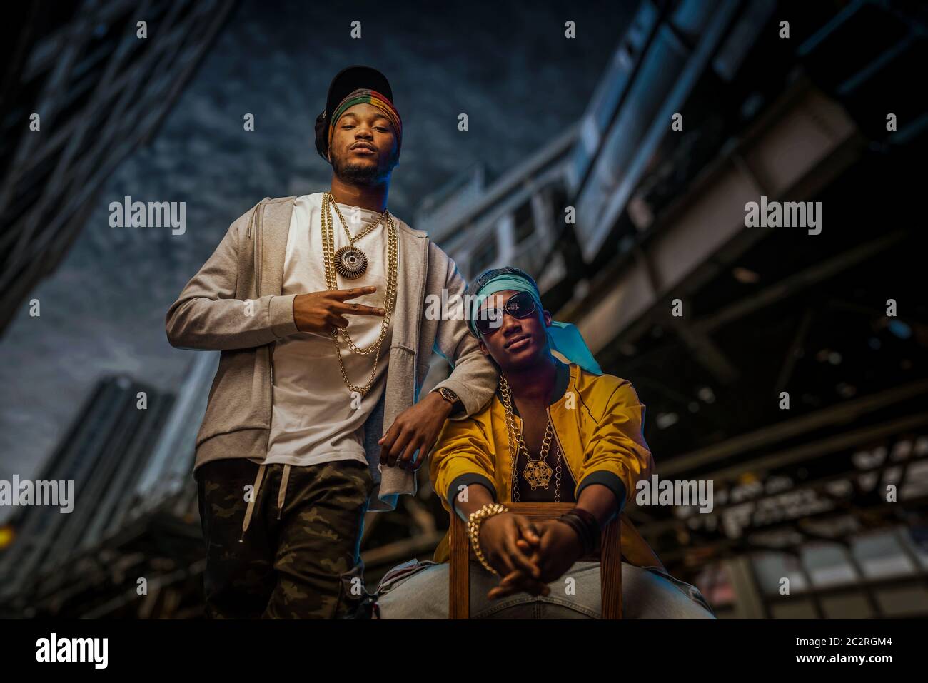 Two black rappers poses on night city street, skyscrapers on background ...