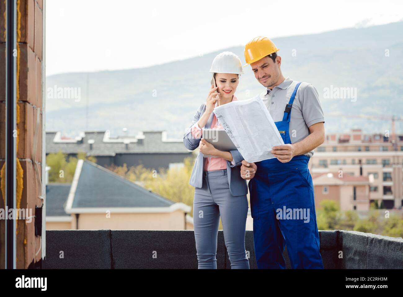 Worker and developer on construction site looking into plan with ...