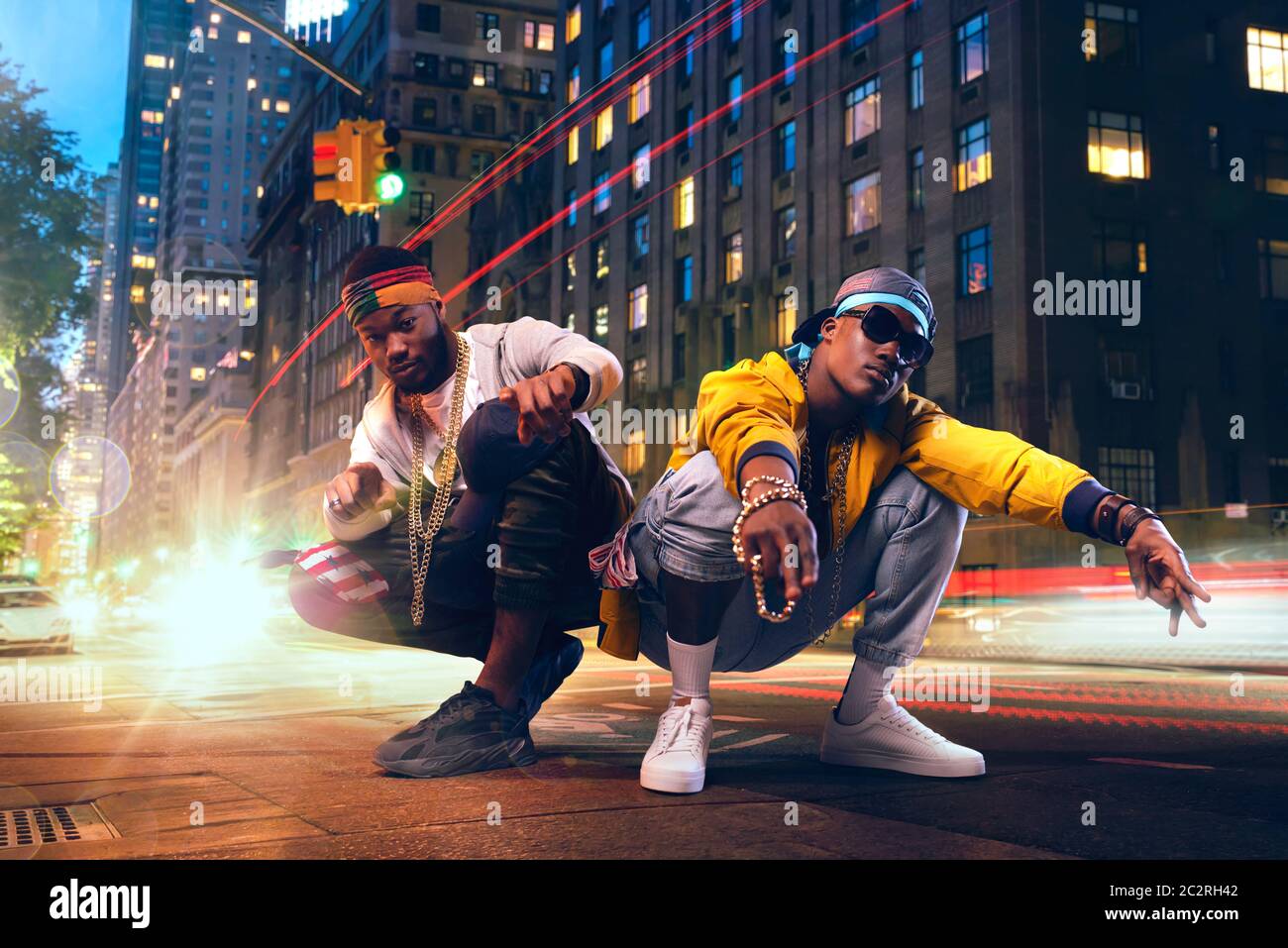 Two black rappers dancing on city street, car lights exposure effect ...