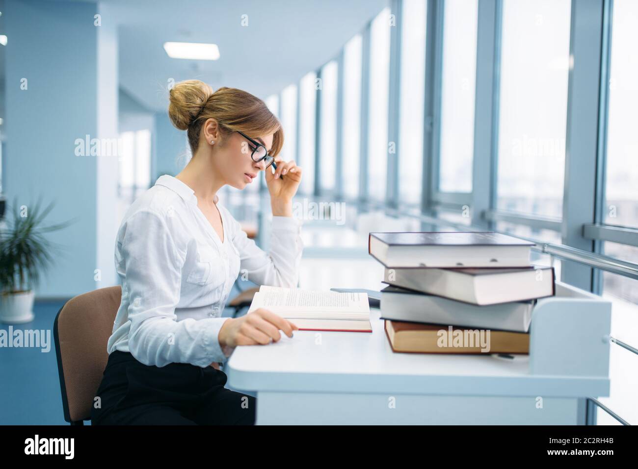 Pretty woman in glasses learning book in library. Female person in ...