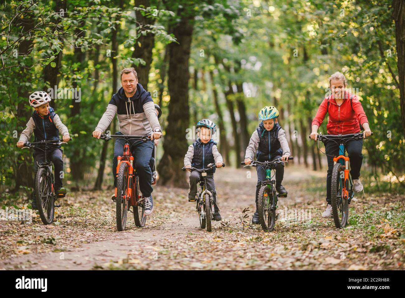 parents and kids cycling on forest trail. Young family in warm clothes ...