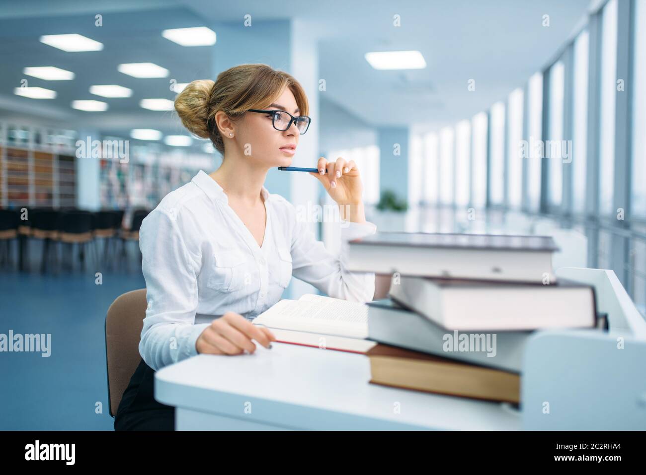 Pretty woman in glasses learning book in library. Female person in ...