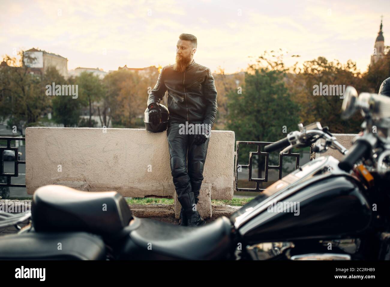 Vintage chopper, biker in leather clothes with helmet in hands on ...