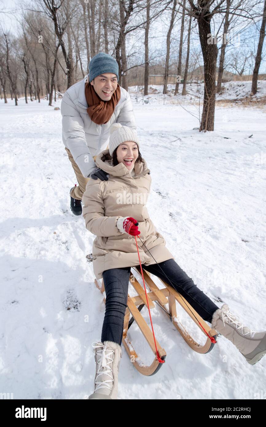 The young couple sledding in the snow Stock Photo - Alamy
