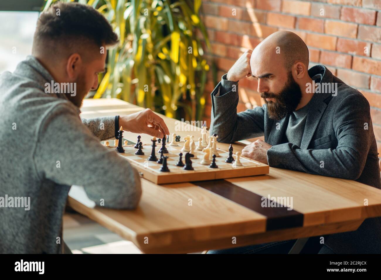 Male chess players playing at board, move the black elephant. Two ...