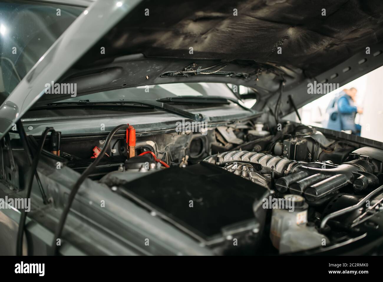 Car with opened hood and the wire for battery recharging, nobody ...