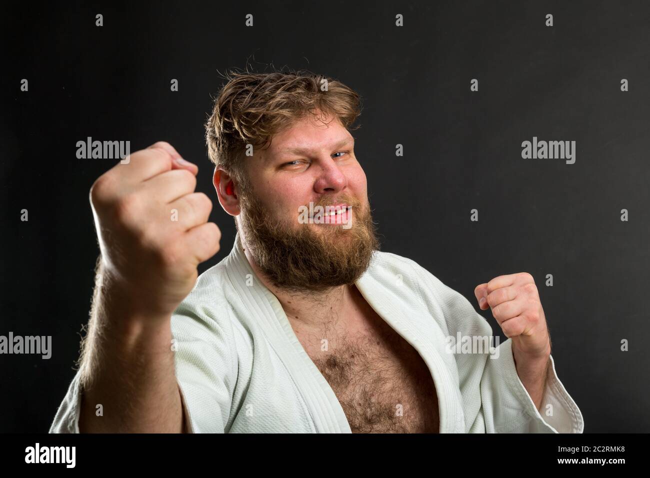 Smiling bearded karate fighter in white kimono shows fists Stock Photo ...