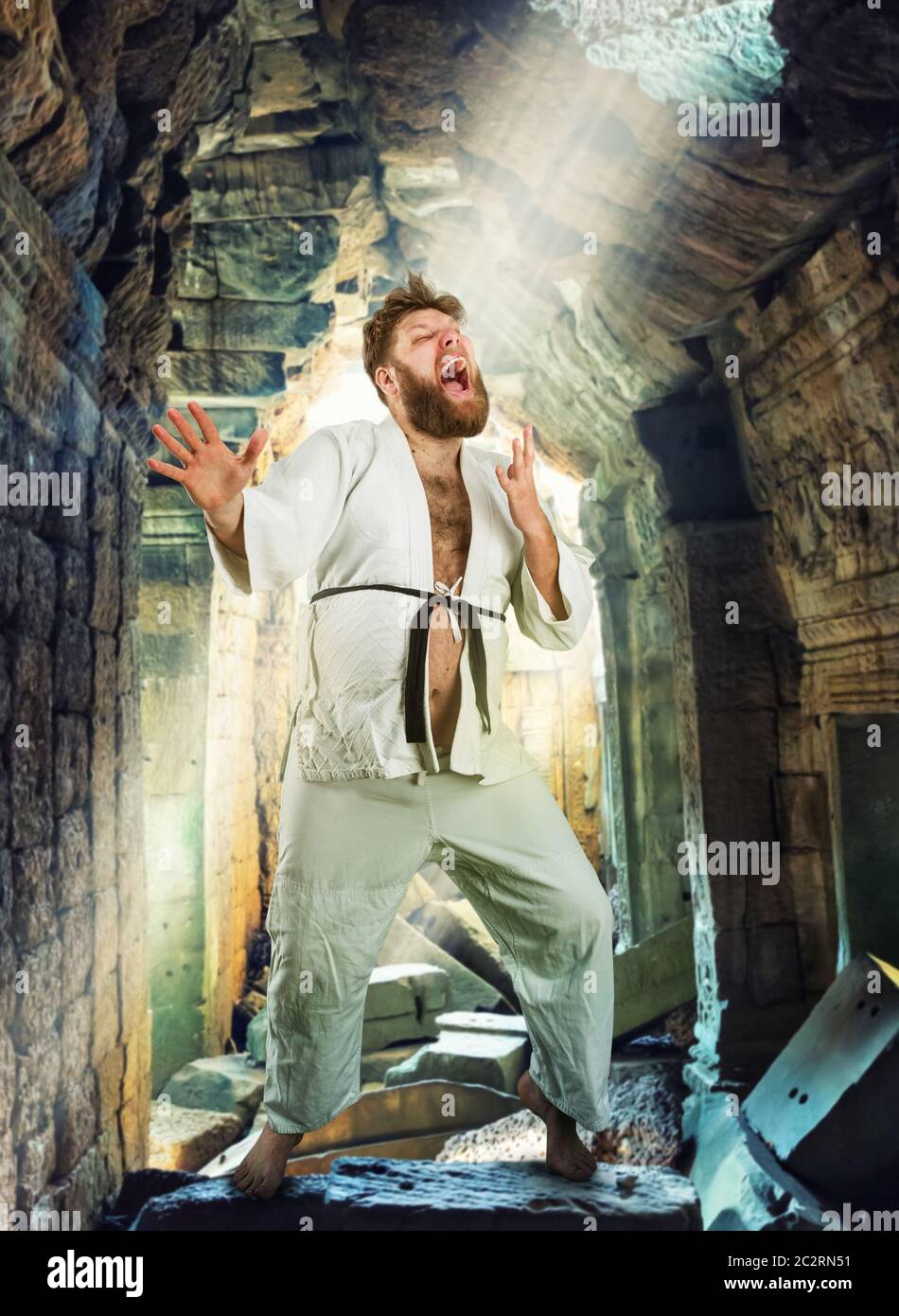 Aggressive fat karate fighter in white kimono in an old brick temple ...