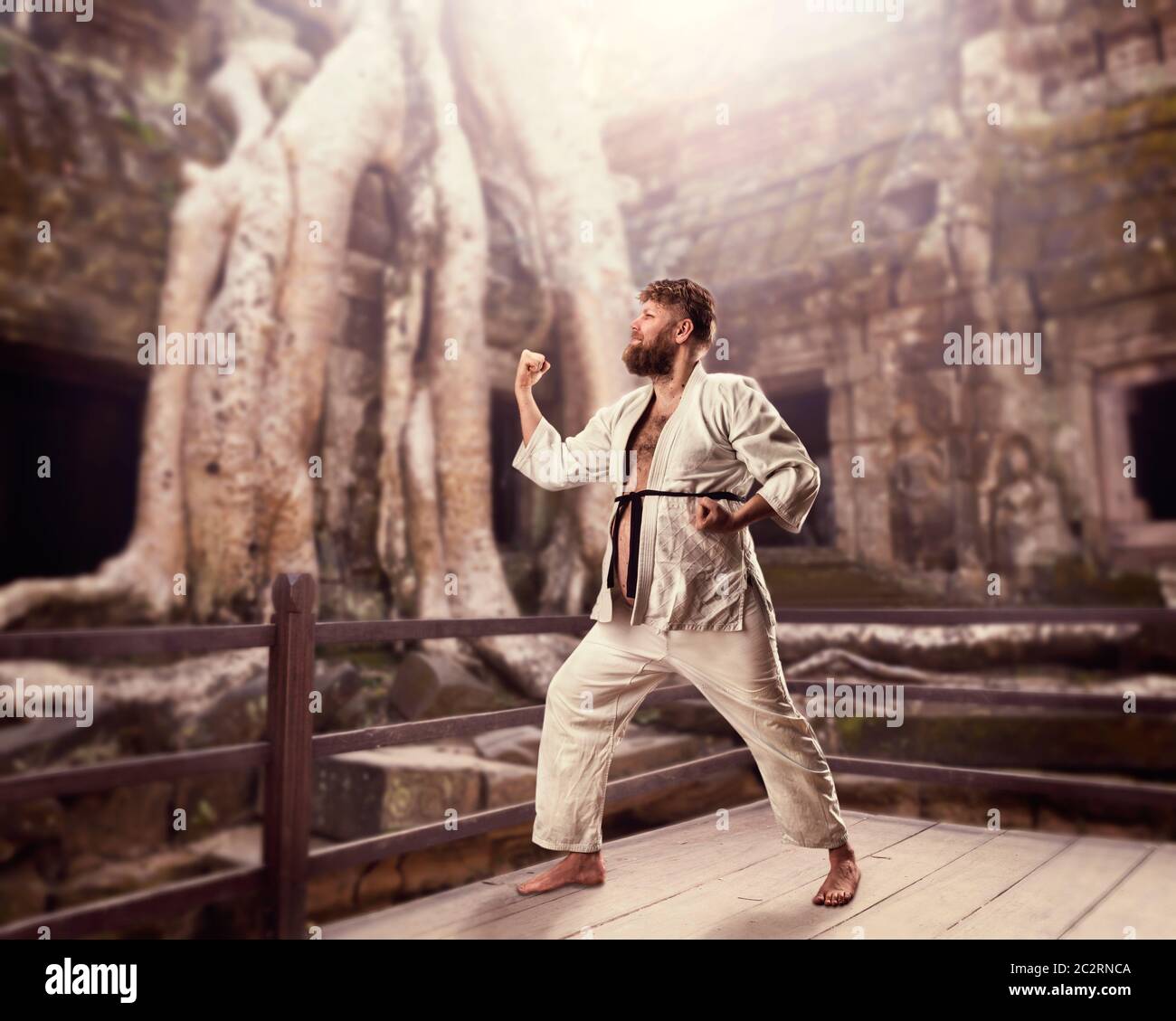 Fat bearded karate fighter in white kimono doing kata against temple ...