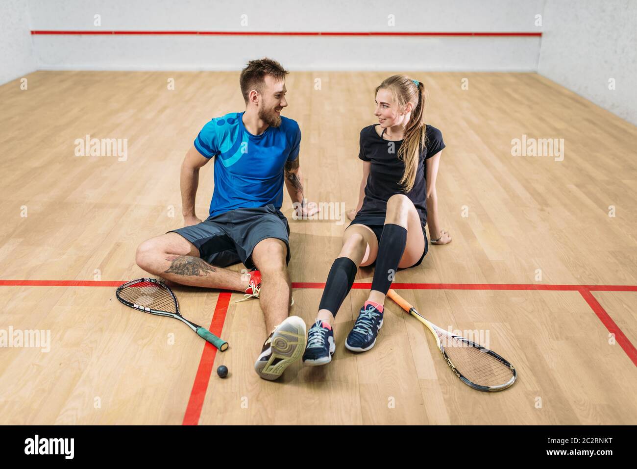 Squash game concept, rackets with ball, young couple sitting on the ...