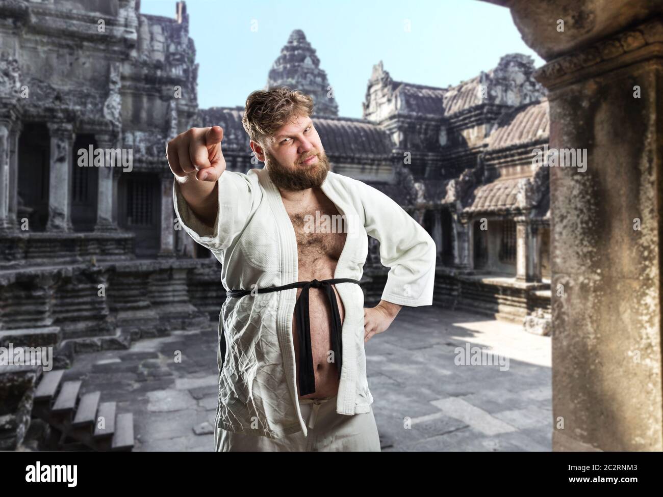 Bearded karate fighter in white kimono in the temple points at you ...