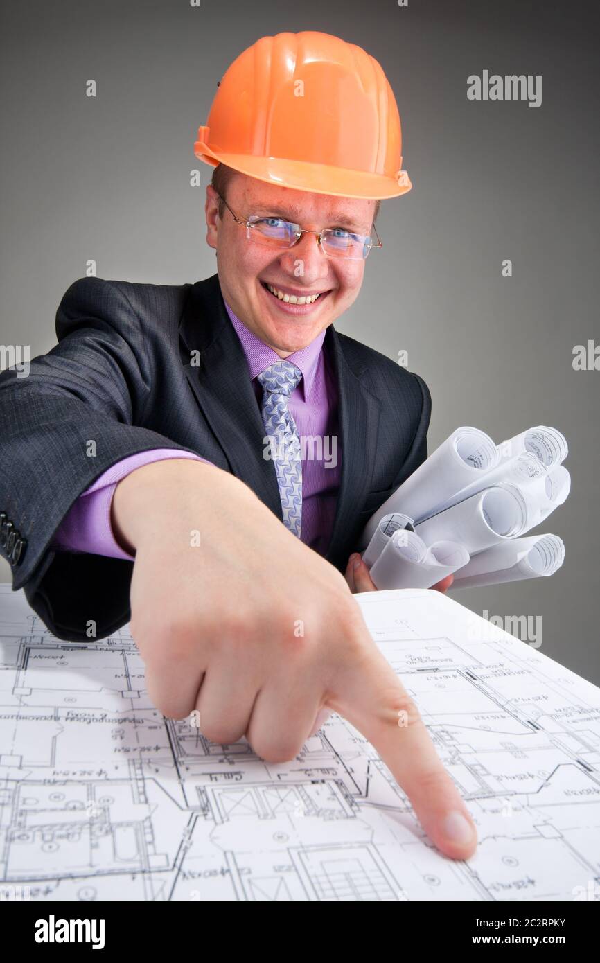Happy contractor in hardhat pointing to plans Stock Photo - Alamy