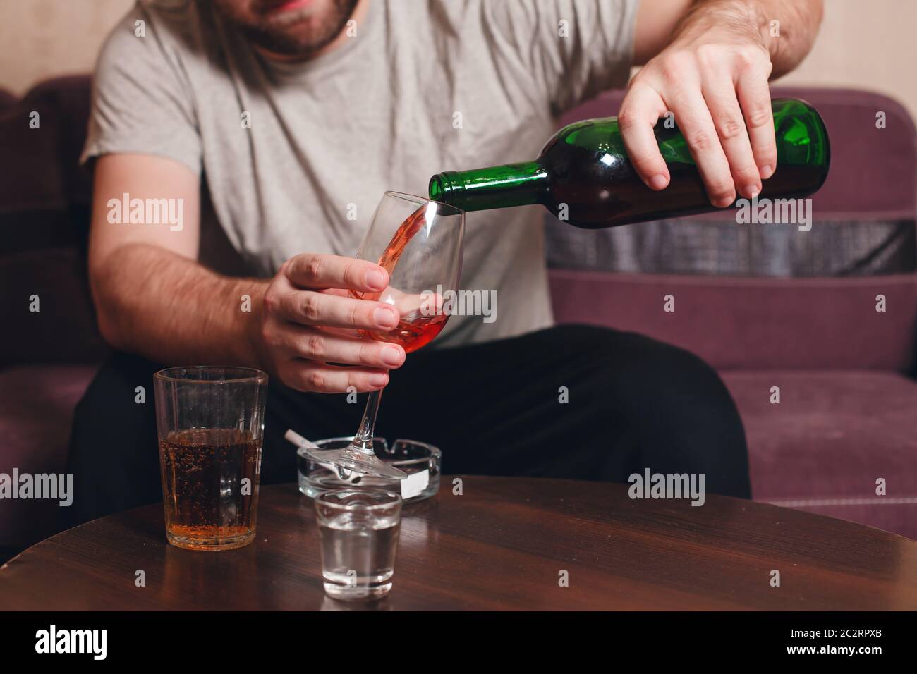 Lonely man drinking behind bottles of alcohol Stock Photo - Alamy