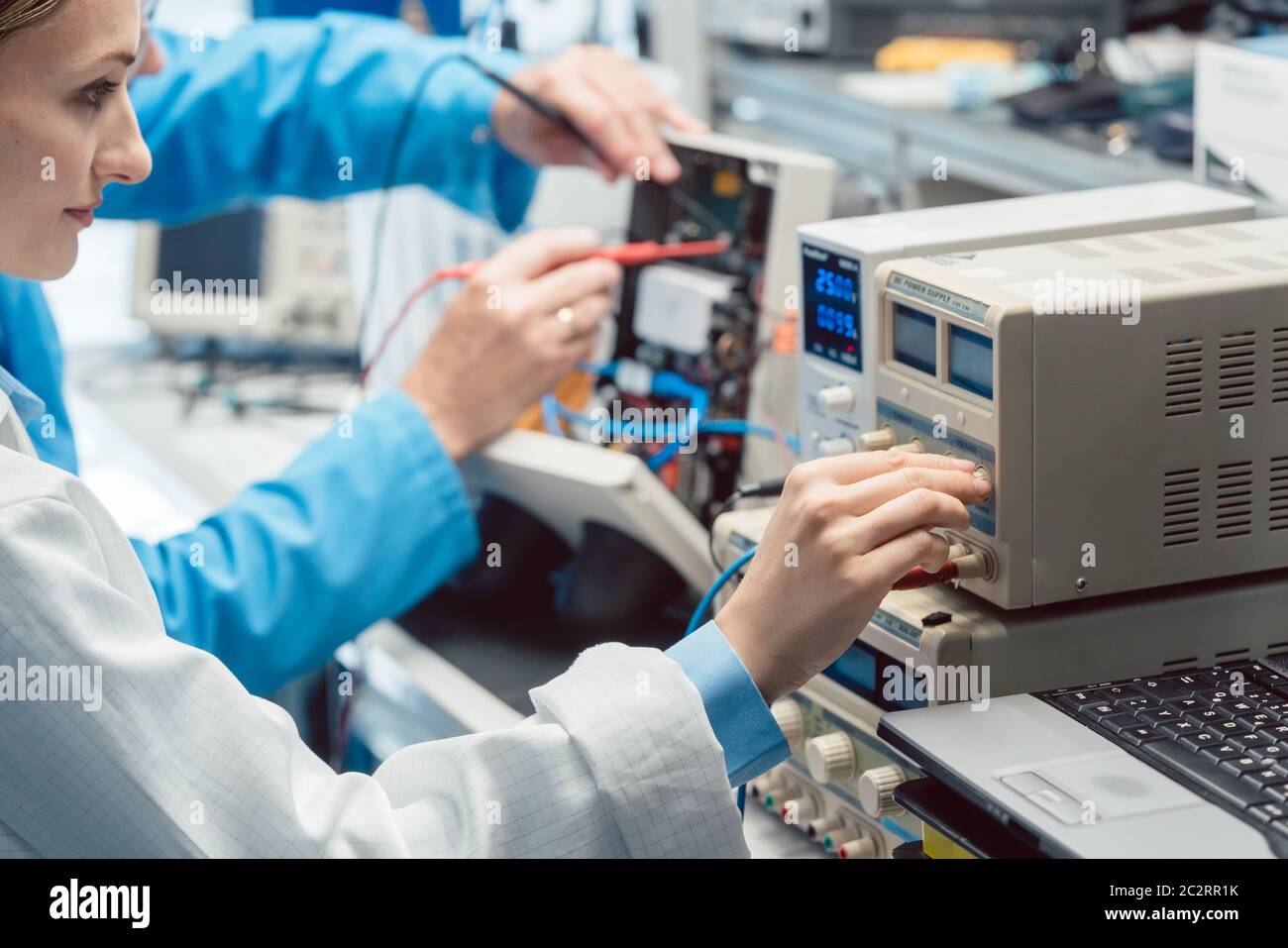 Two electronic engineers on the lab test bench measuring a new product ...