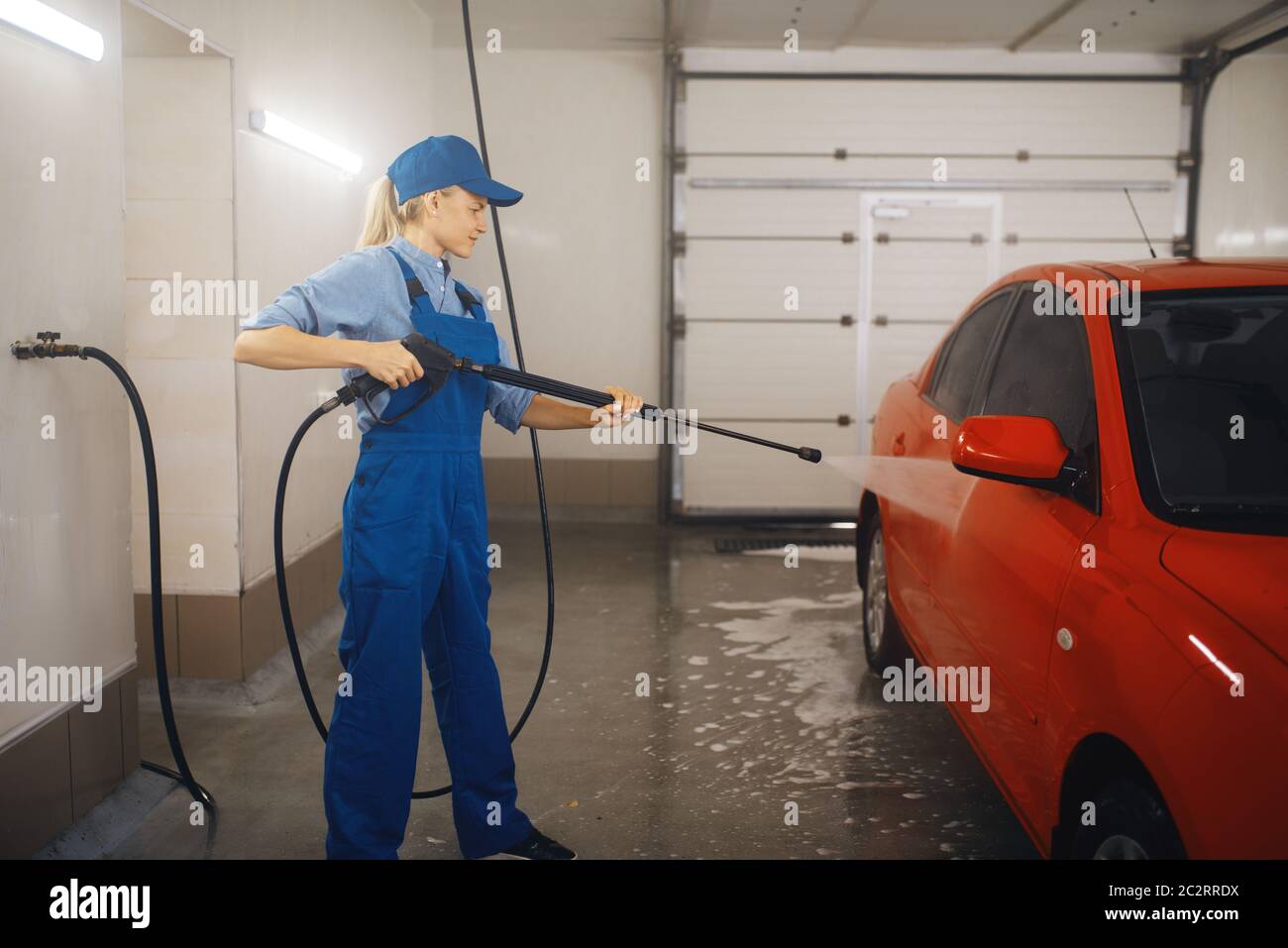 Female washer in uniform cleans the auto with high pressure gun in ...