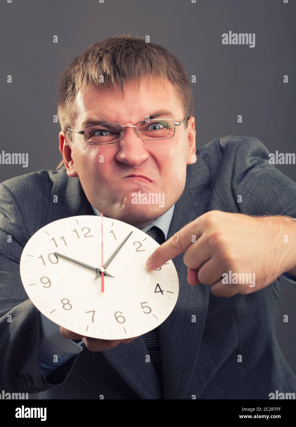 Young man in a suit holding a clock Stock Photo - Alamy