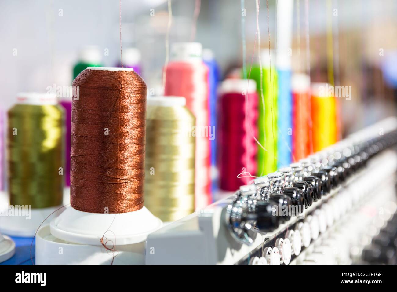 Spools of new threads closeup, sewing machine. Cloth factory, weaving ...