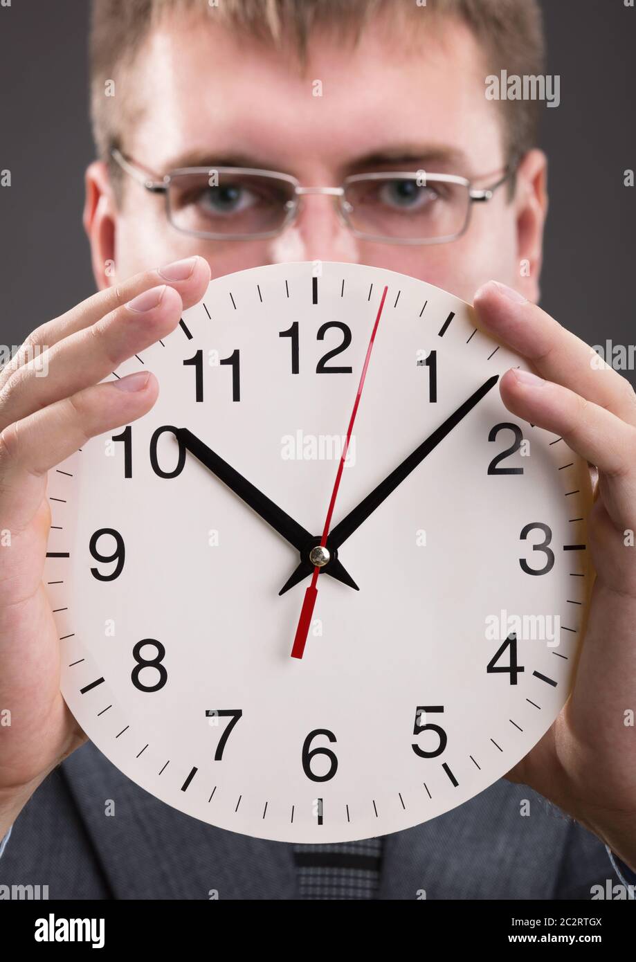 Young man in a suit holding a clock Stock Photo - Alamy