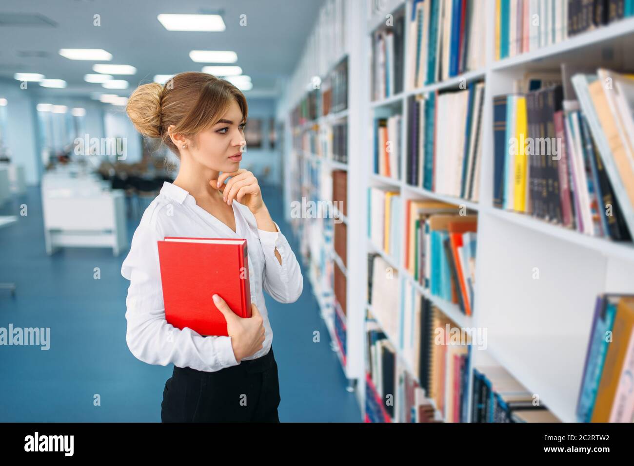 Young woman looking book at the shelf in library. Female person in ...