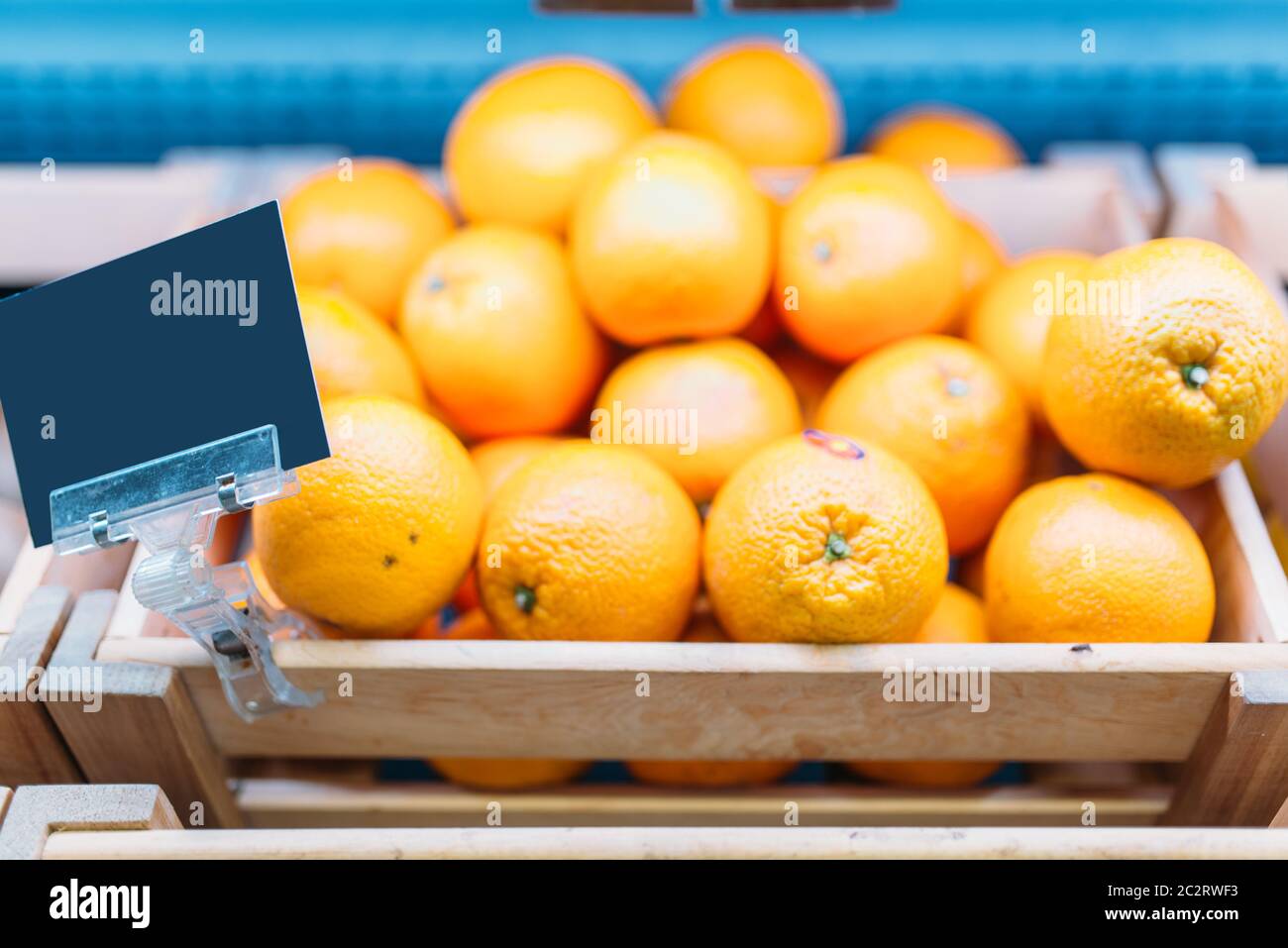 Box with fresh oranges on stand in food store, nobody, empty price ...