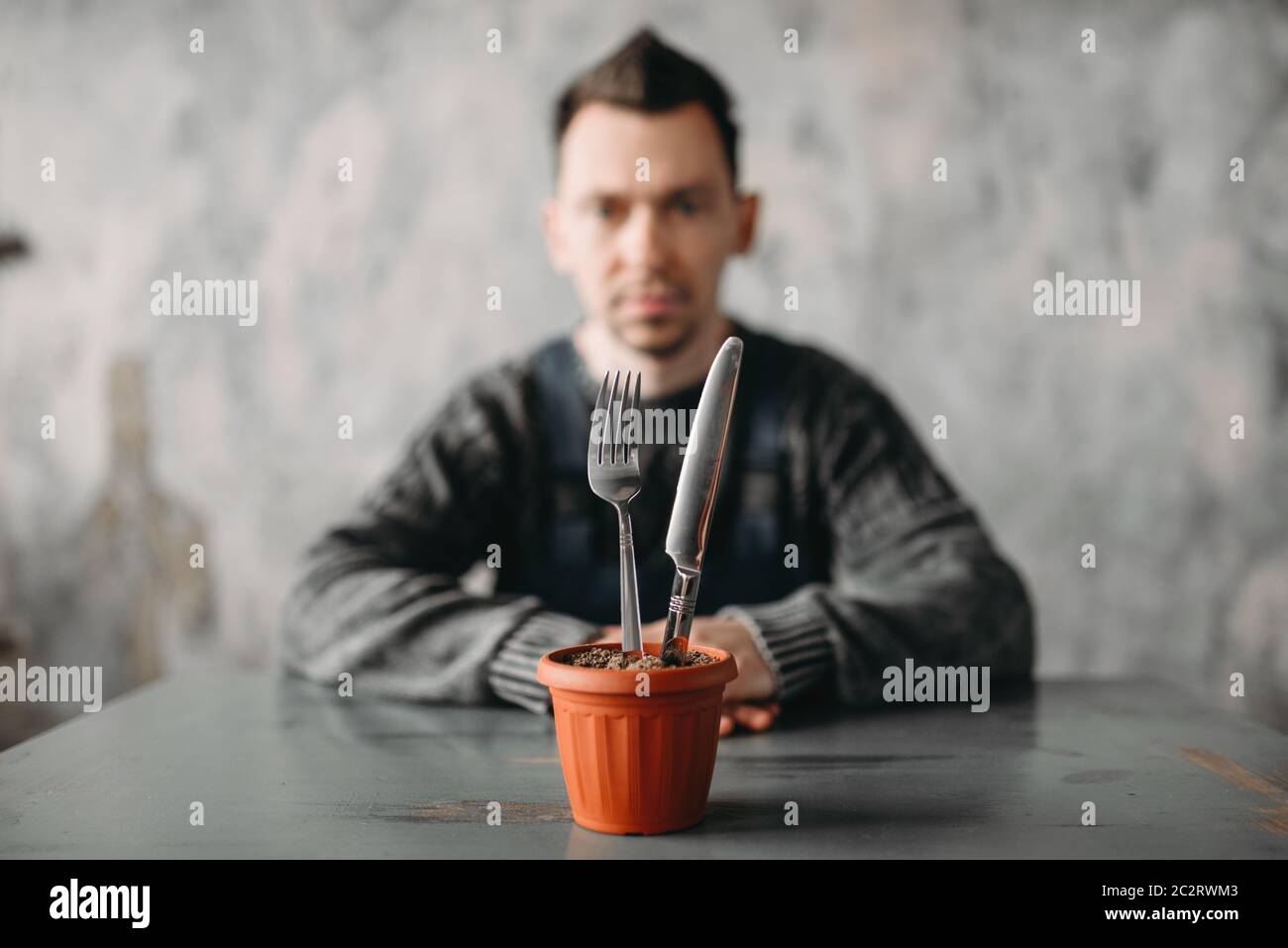 Autistic man sitting against pot with fork and knife instead of plants ...