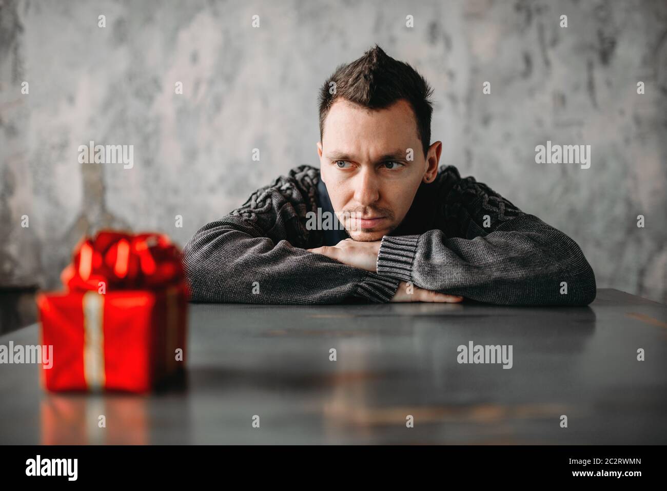 Autistic man sitting against gift in wrapping paper. Alone guy in ...