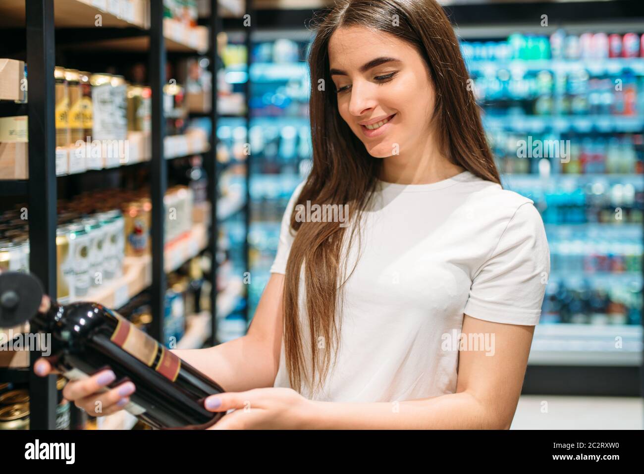 Woman choosing wine in alcohol section in market. Female customer in ...