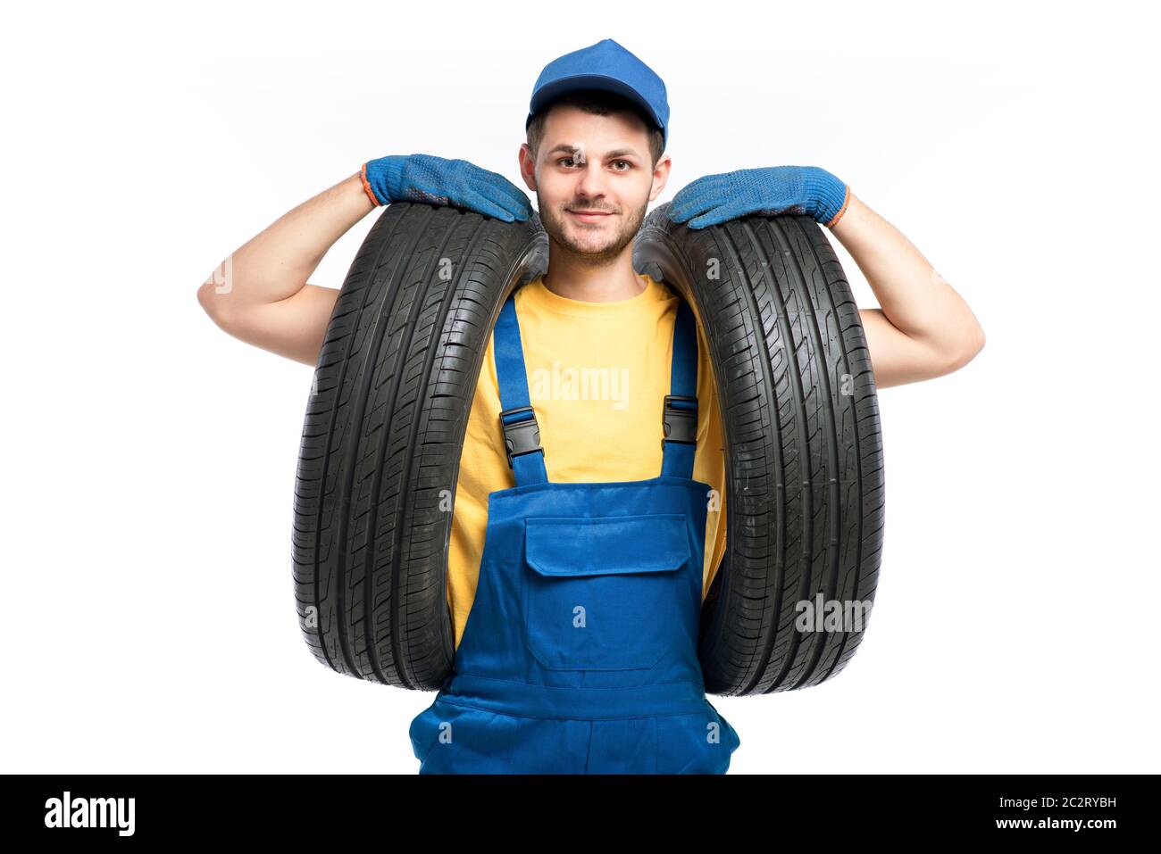 Tire service worker in blue uniform holds car tyres in hands, white ...
