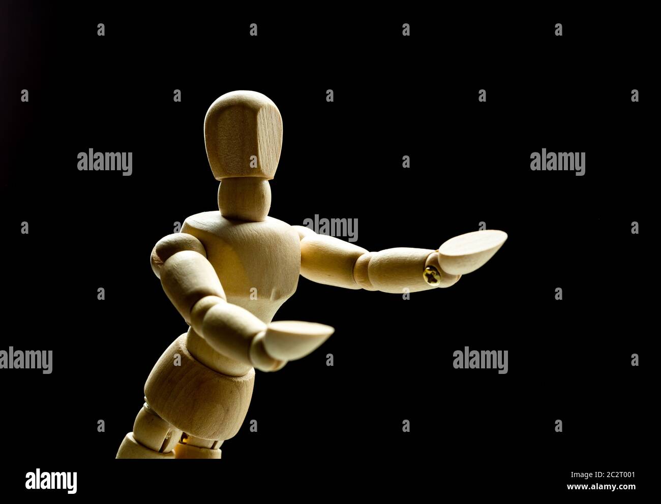 Human wood manikin showing something on black Stock Photo - Alamy