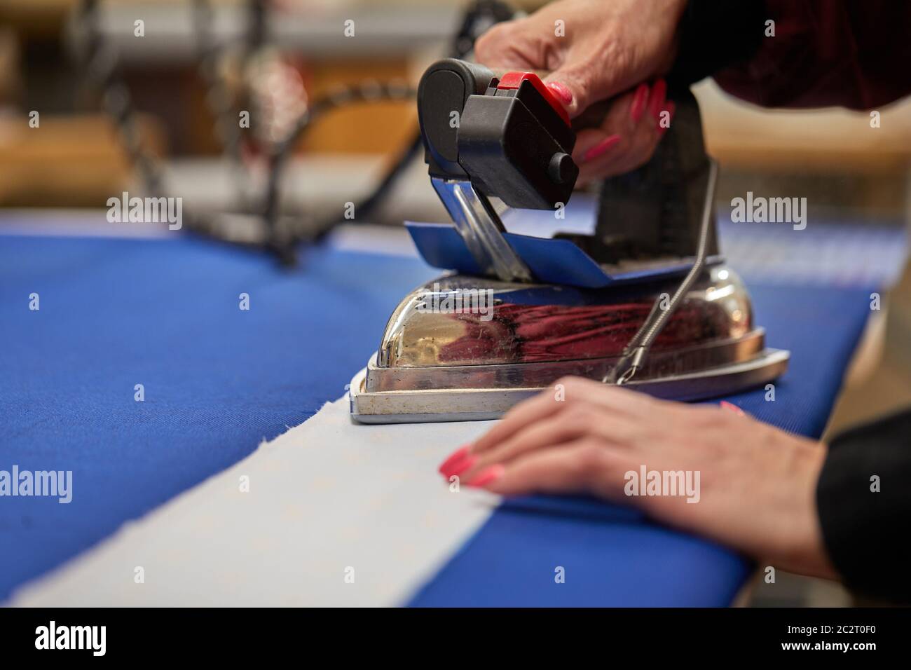 Tailor ironing the fabric. seamstress irons dress in a sewing workshop ...