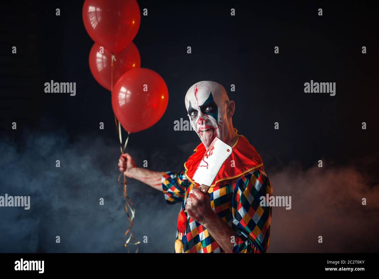 Spooky bloody clown with knife holds air balloons, horror. Man with ...