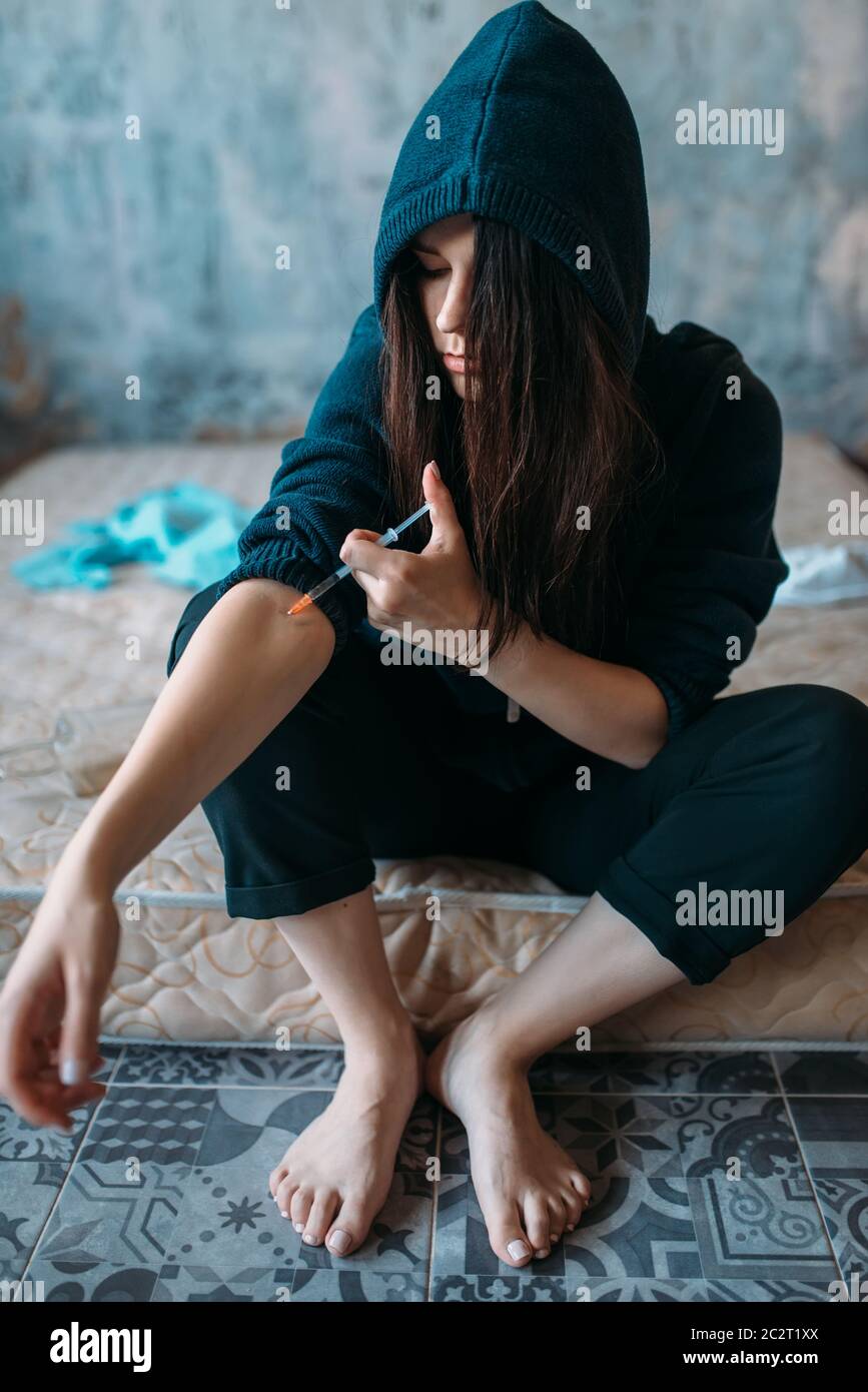 Female junkie with a syringe doing an injection dose in the arm ...