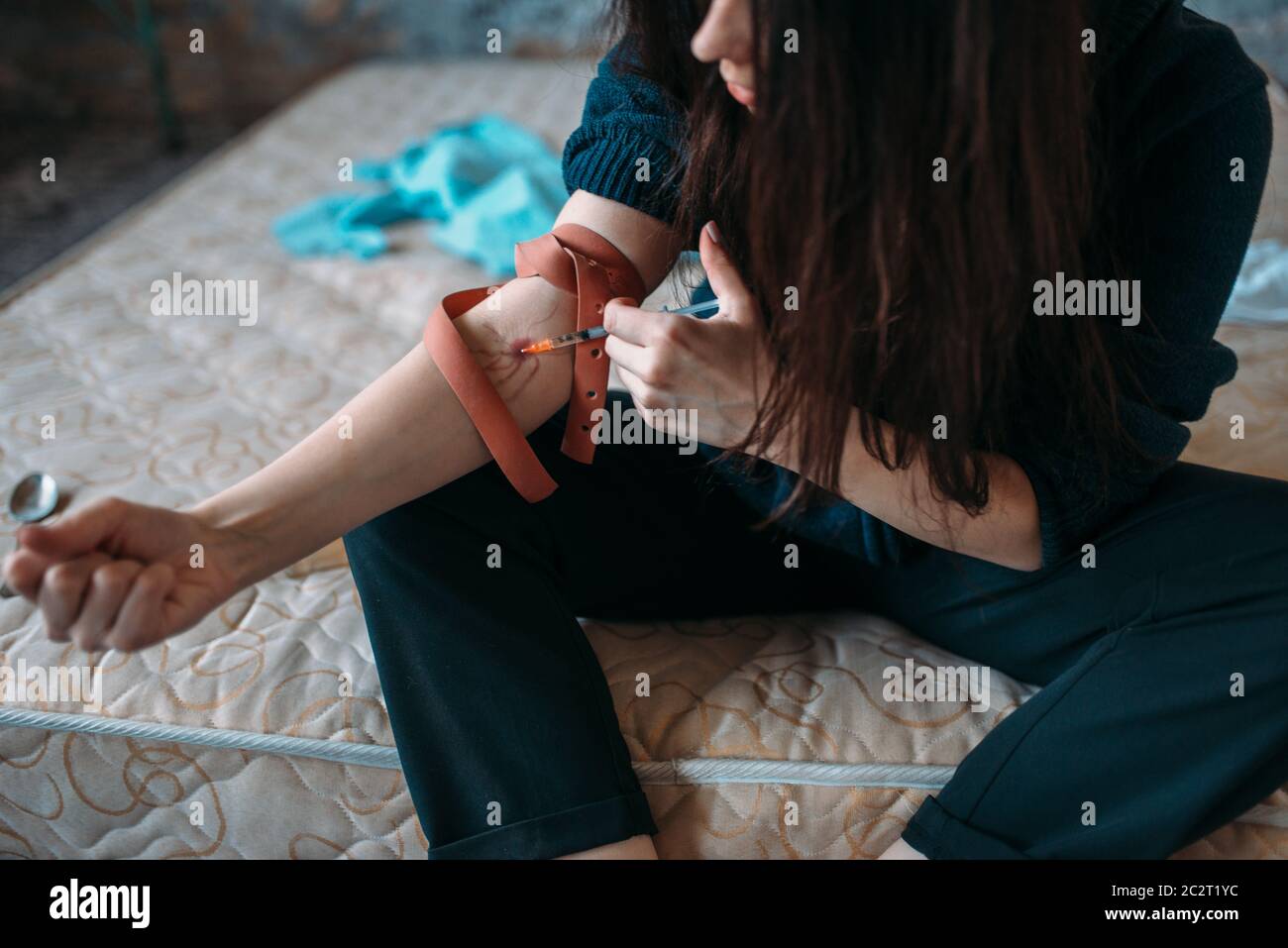 Female junkie with a syringe doing an injection dose in the arm ...