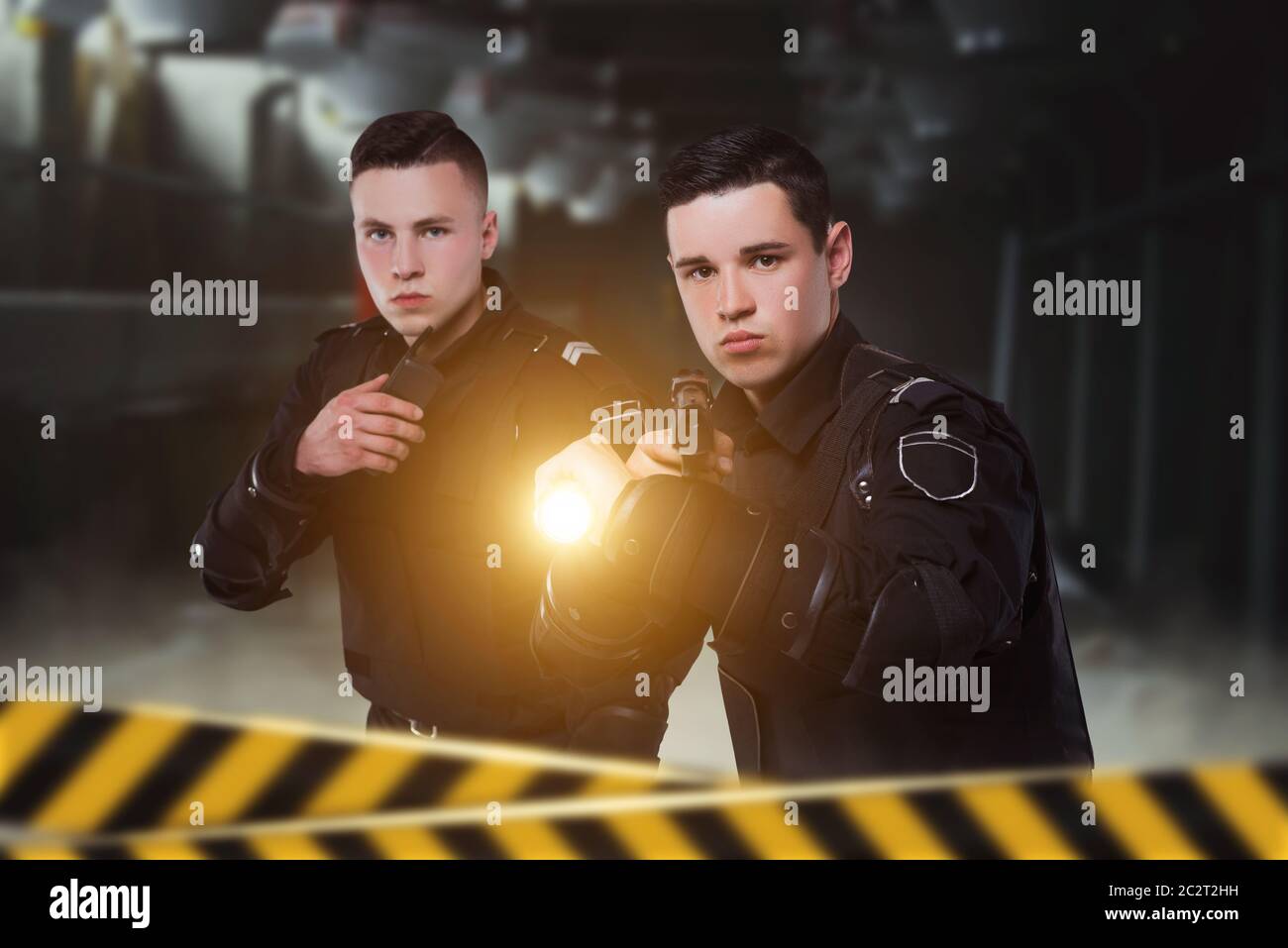 Cops with guns and lantern, black uniform and body armor, front view ...