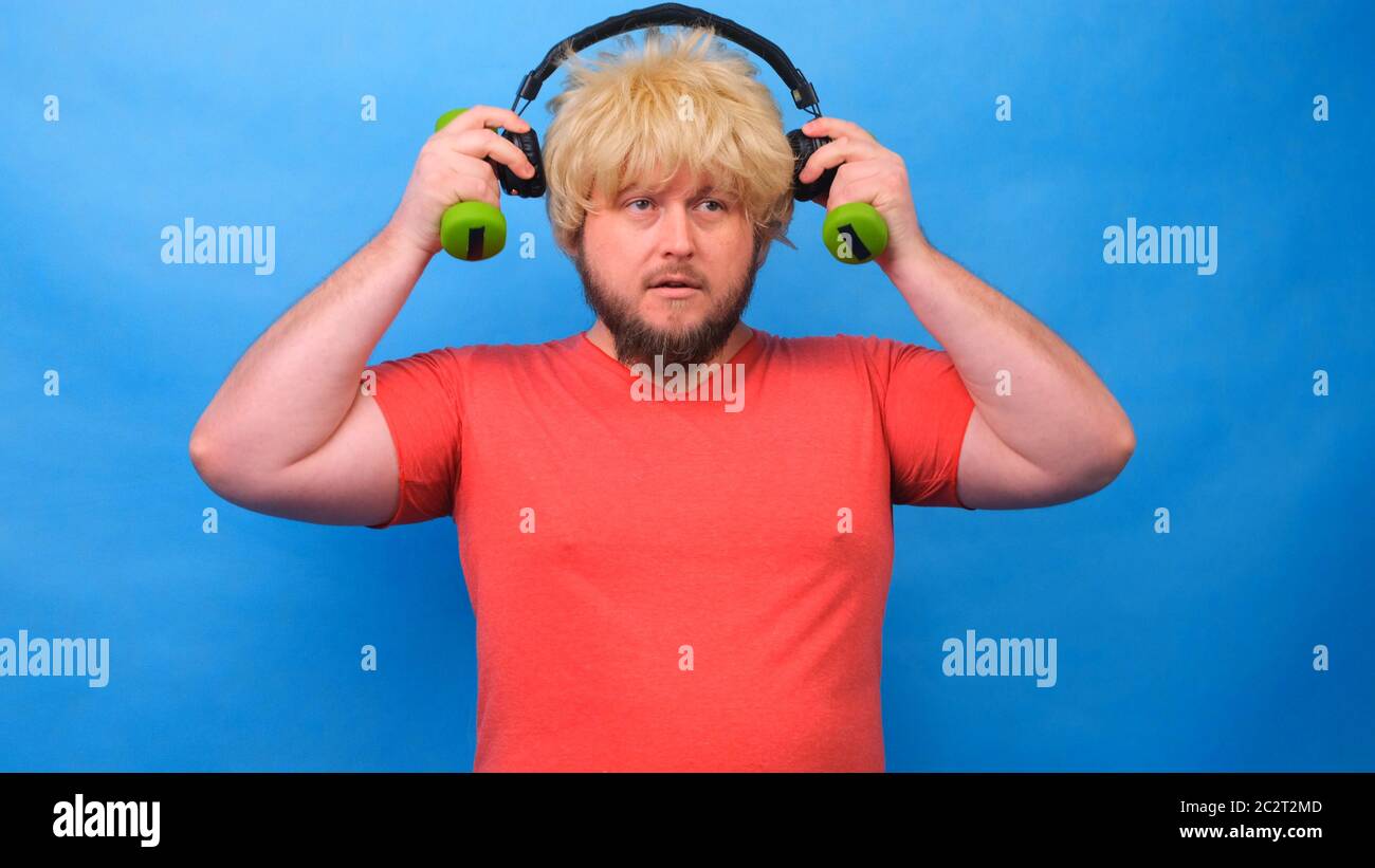 Funny fat man freaky in a wig and a pink t-shirt with dumbbells in his ...