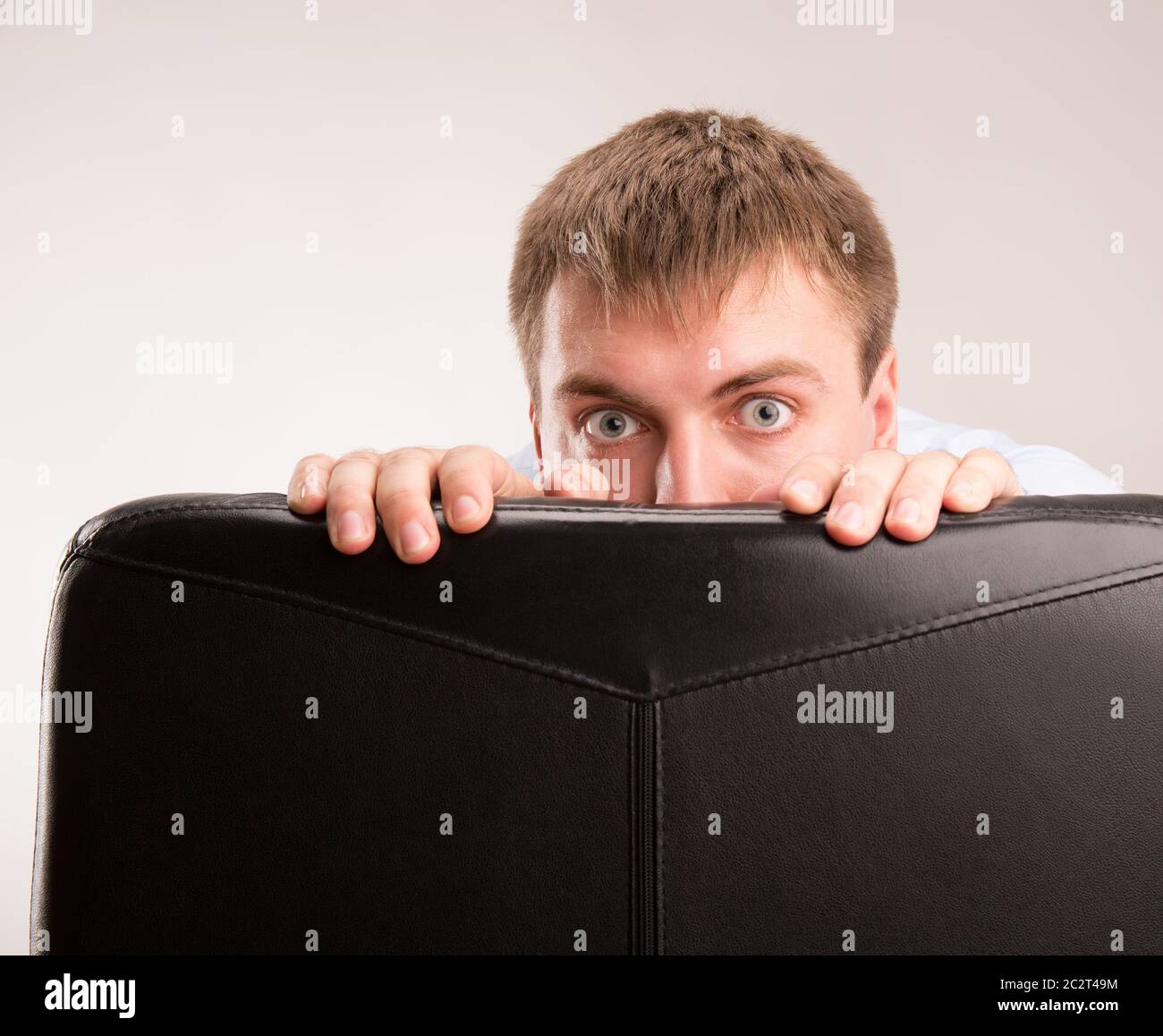 A young man hiding behind a office chair Stock Photo - Alamy
