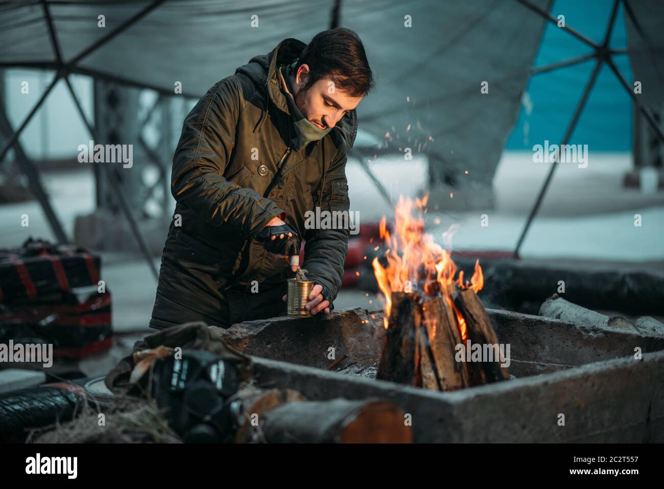 Stalker, male person cooking canned food on fire. Post apocalyptic ...