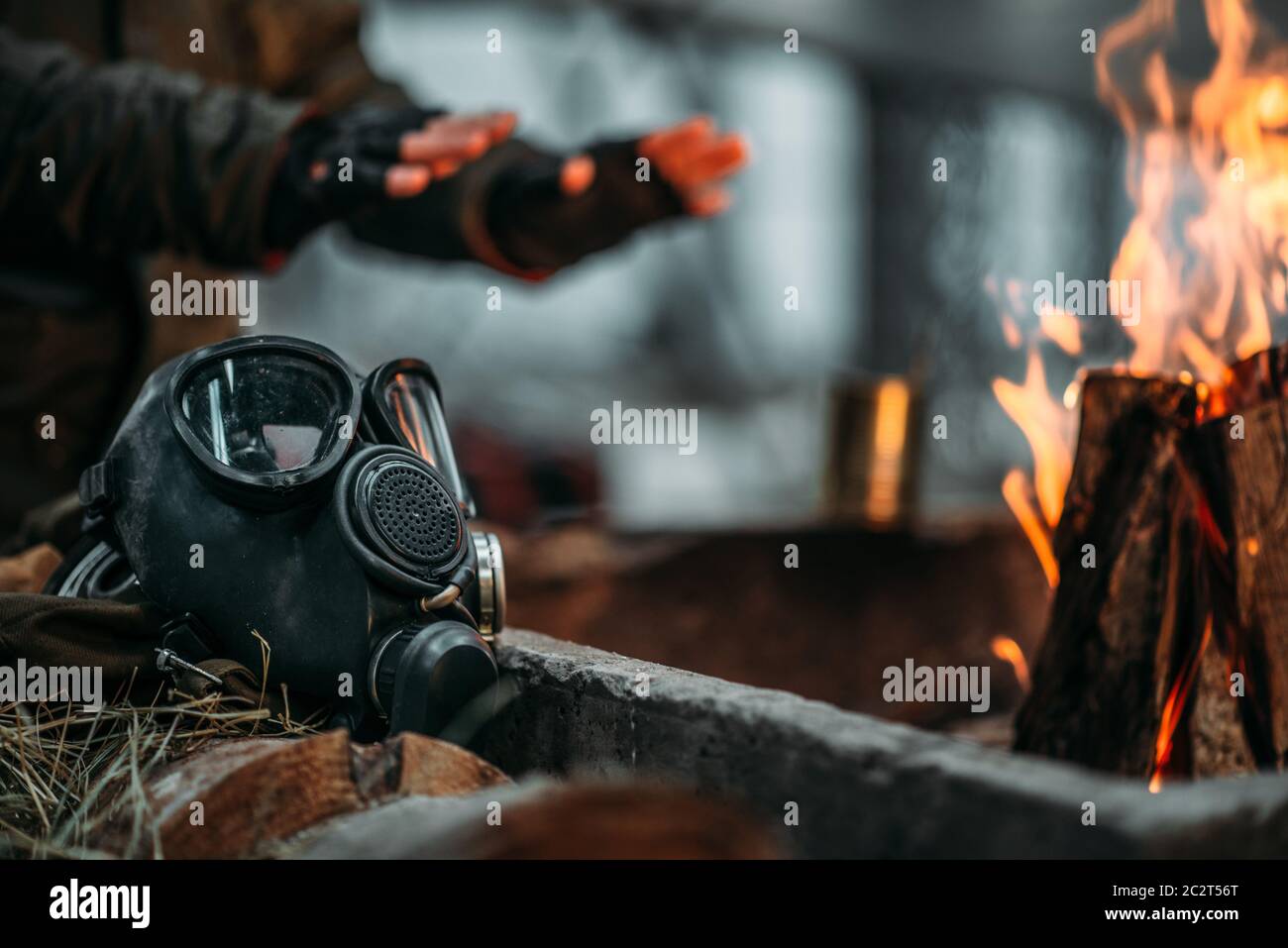 Stalker, male person warms his hands on fire. Post apocalyptic ...