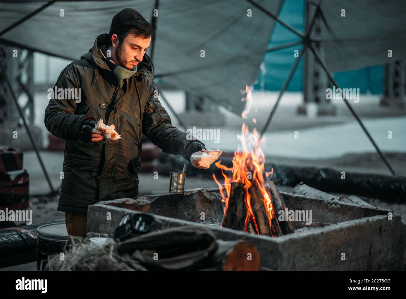 Stalker cooking food on fire, dog on background. Post apocalyptic ...