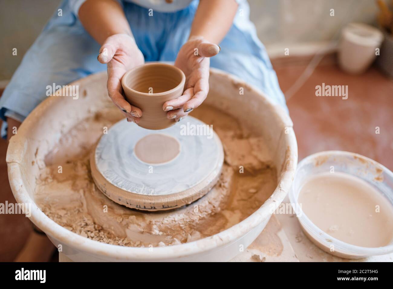 Female master holds wet pot over the pottery wheel. Woman molding a ...