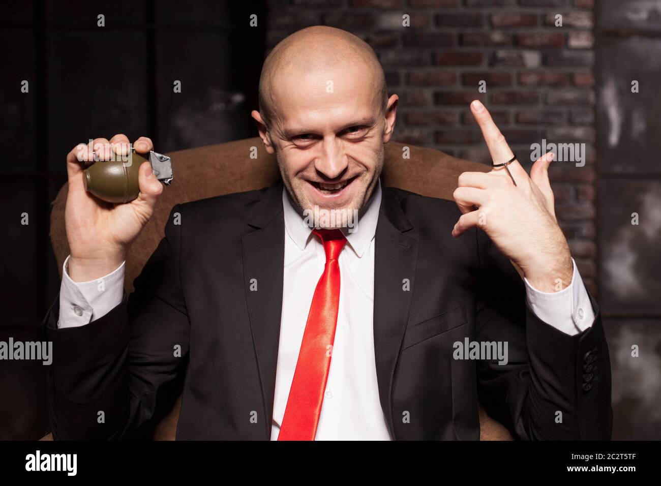 Bald special agent in suit and red tie pulls a grenade pin, dangerous ...