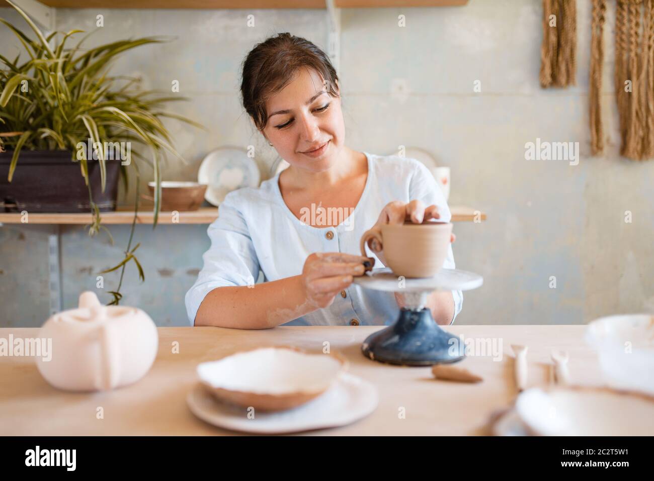 Female potter skins pot, pottery workshop. Woman molding a bowl ...